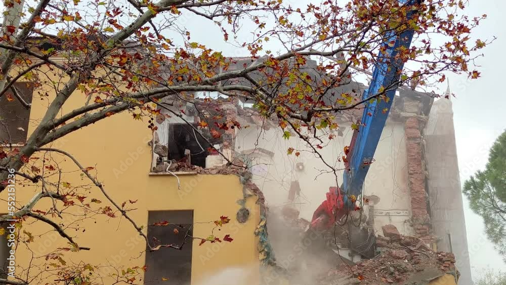 Demolition of a building with a mechanical shovel on a construction ...