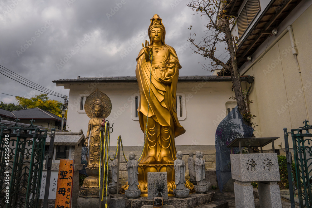 This image shows a gold statue in front of Japan shrine with a moody ...