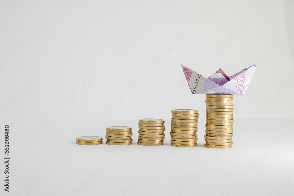 Five hundred euro banknote folded as sailboat on top of stacked euro ...
