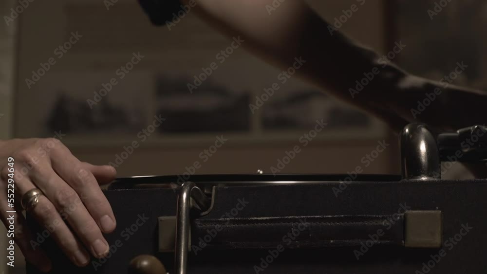 Female hands are slowly turning the handle of the vintage music player ...