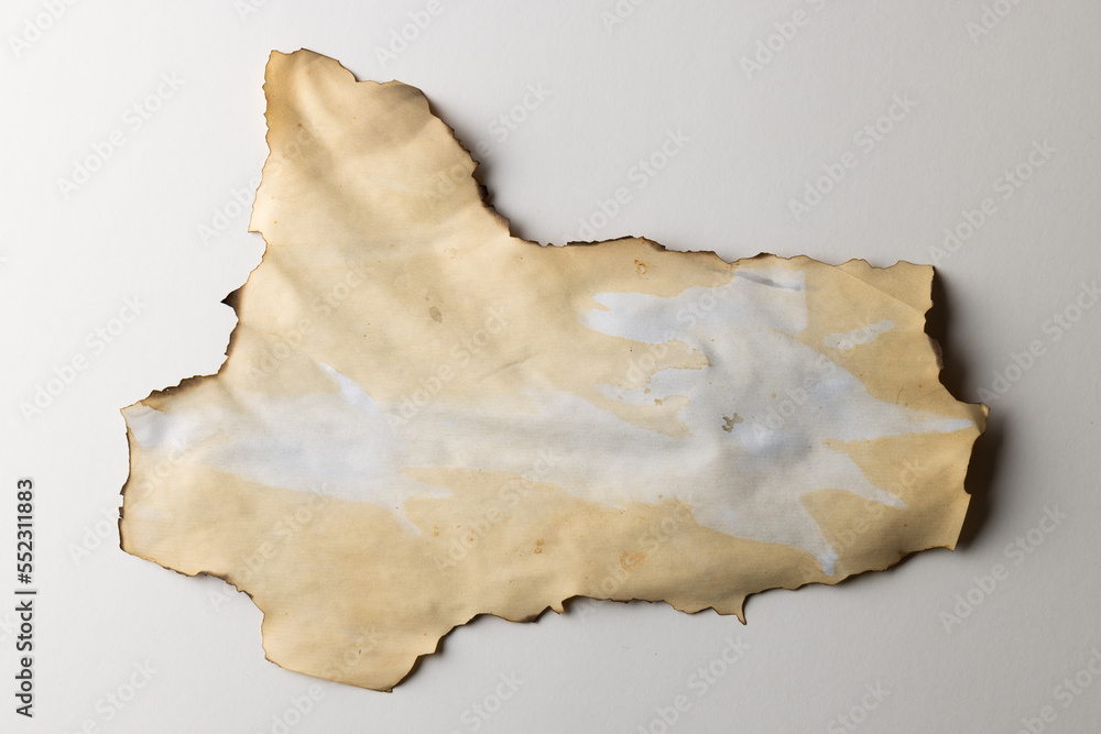 Burned and stained piece of paper with copy space on white background ...