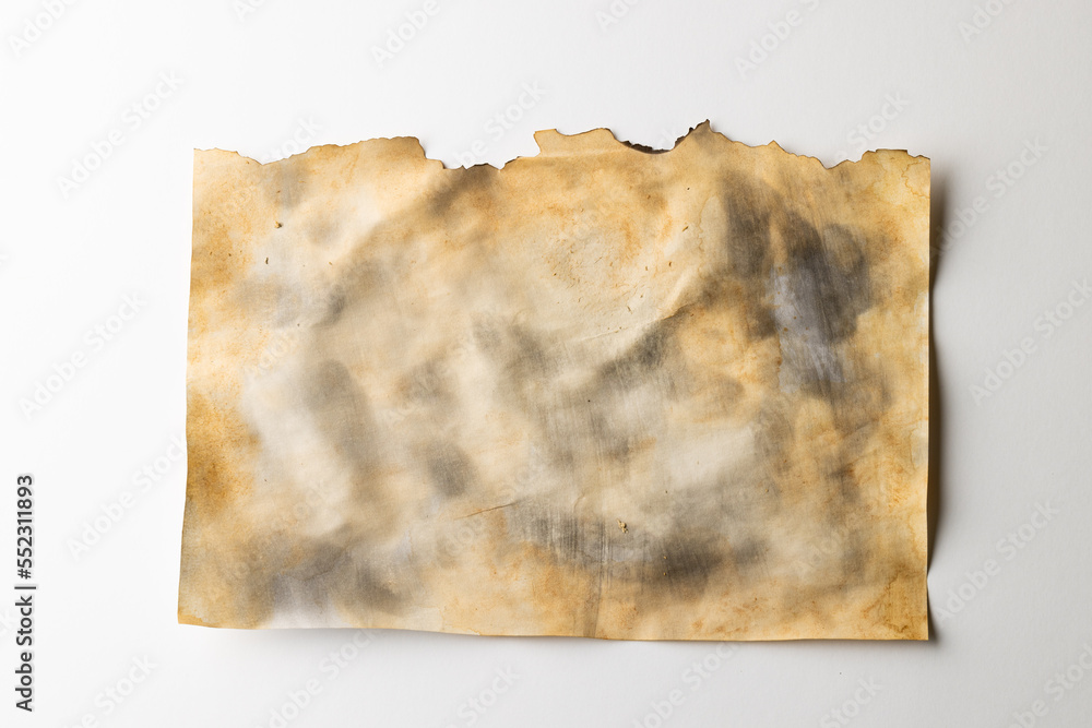 Burned and stained piece of paper with copy space on white background ...