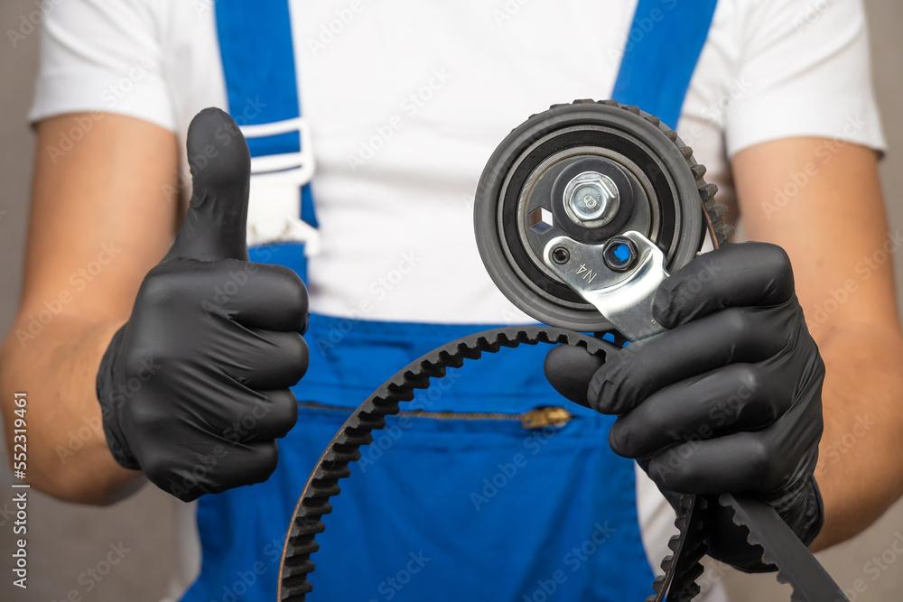 Auto mechanic in blue jumpsuit holds in his hands in black gloves ...