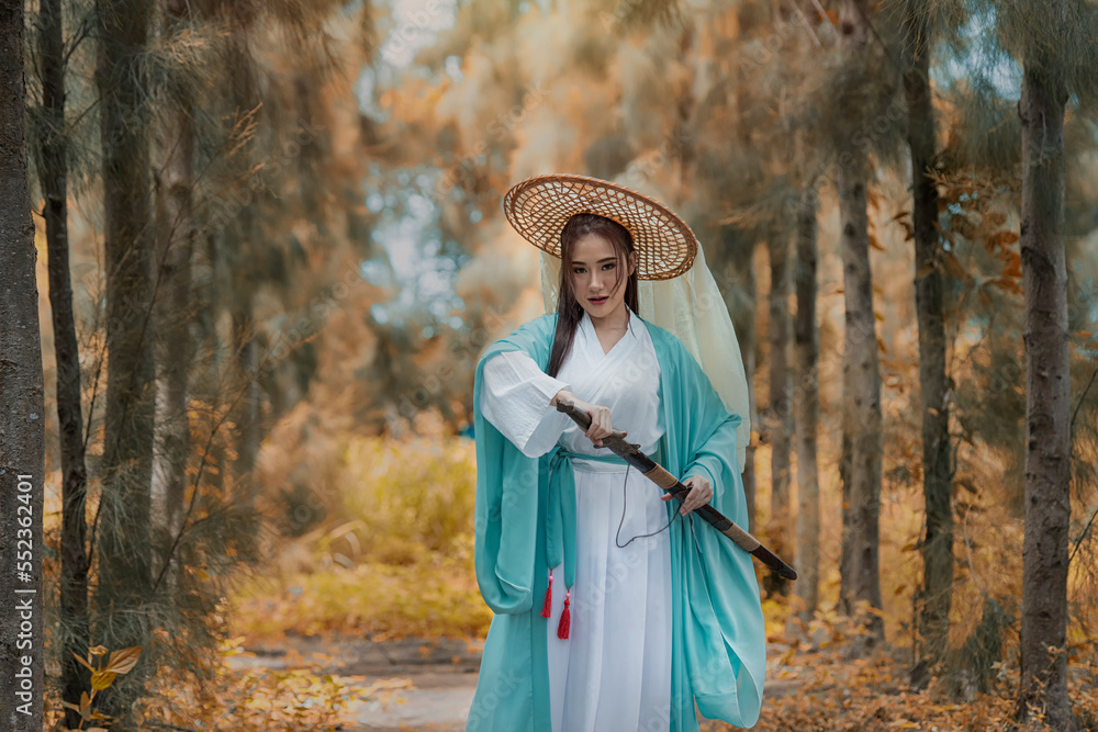 Portrait woman in a Chinese costume with a sword in the forest. Chinese ...