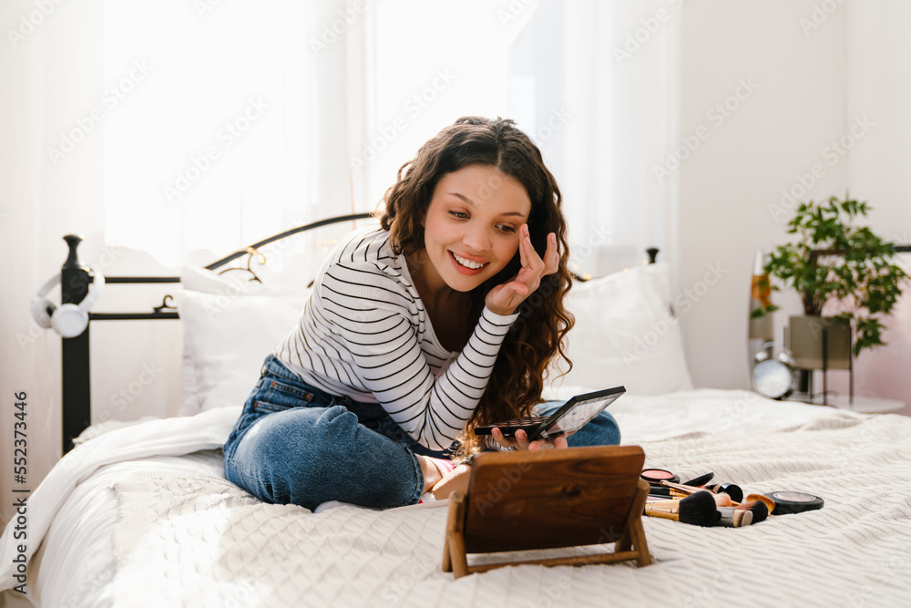 Young girl doing makeup while sitting on bed at home Stock Photo ...