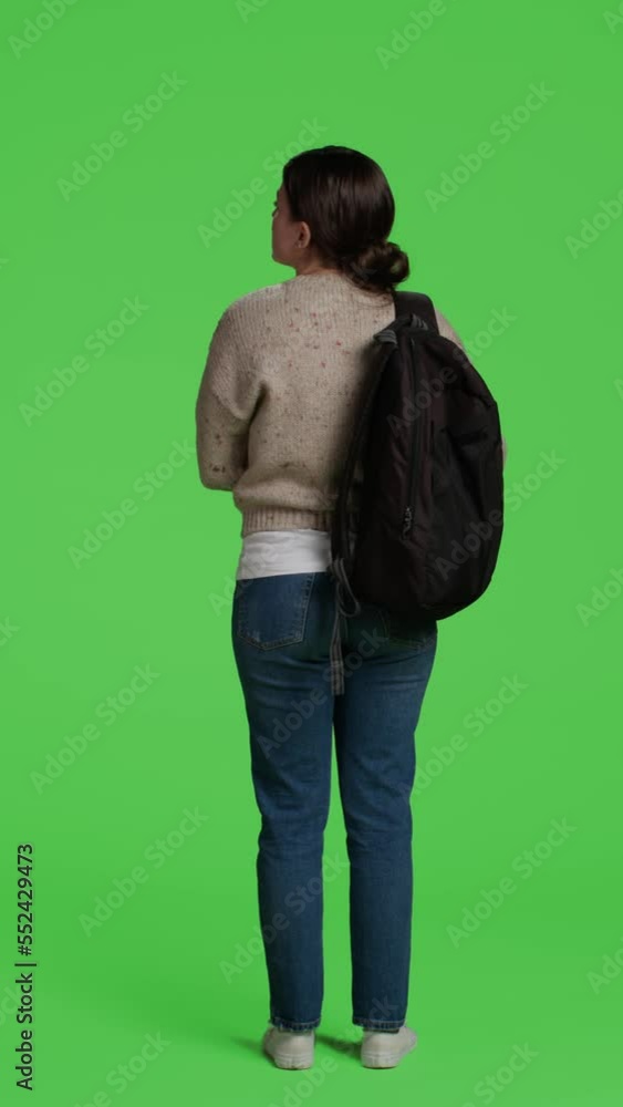 Vertical video: Back view of young adult holding backpack and posing on ...