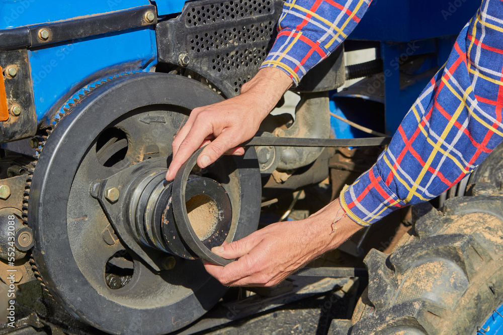 belt replacement on a tractor,the man's hands put a belt on the motor ...