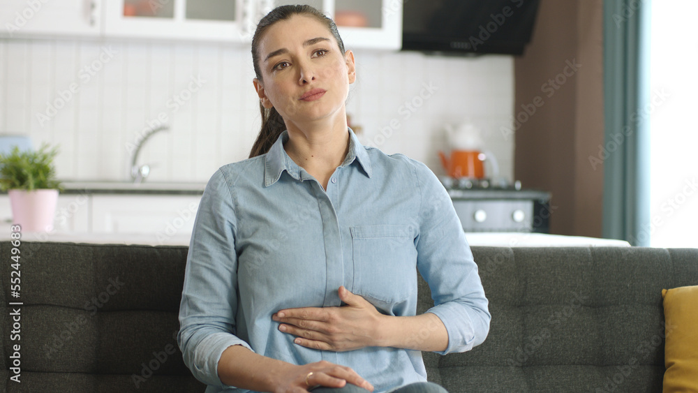 Young woman suffering from stomach spasm, abdominal pain at home ...