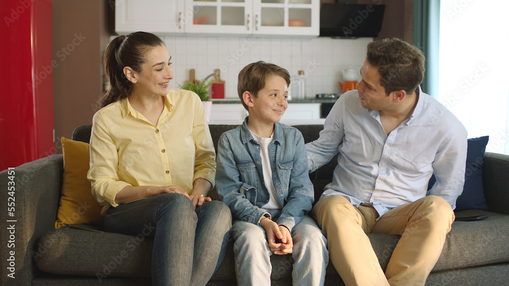 Smiling family resting on sofa and talking to each other. Happy ...