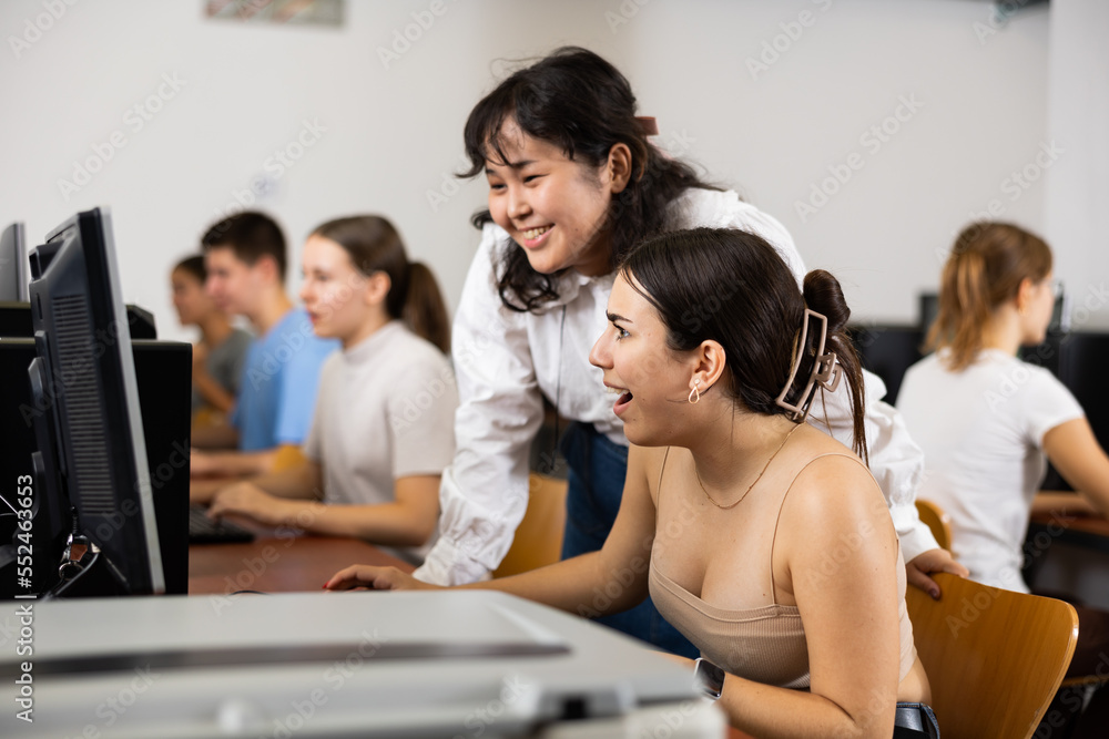 Positive asian and caucasian schoolgirls using PC in computer class ...