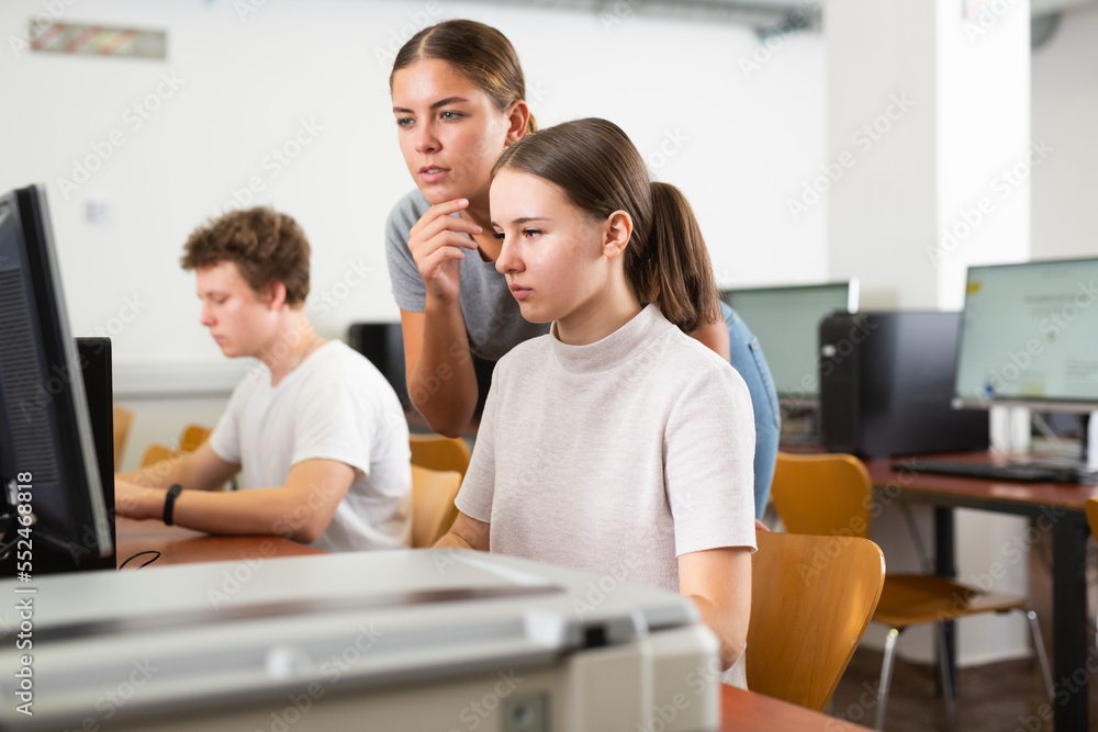 Woman teacher helps girl with learning on computer in school class ...