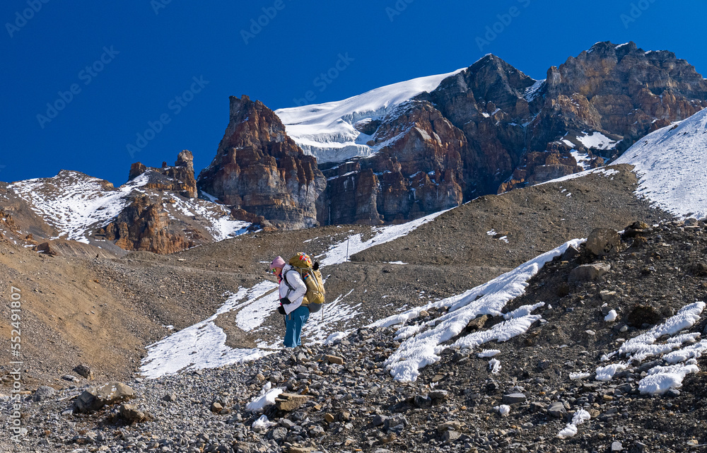 Female trekker walking down Annapurna Circuit Trek path with large ...