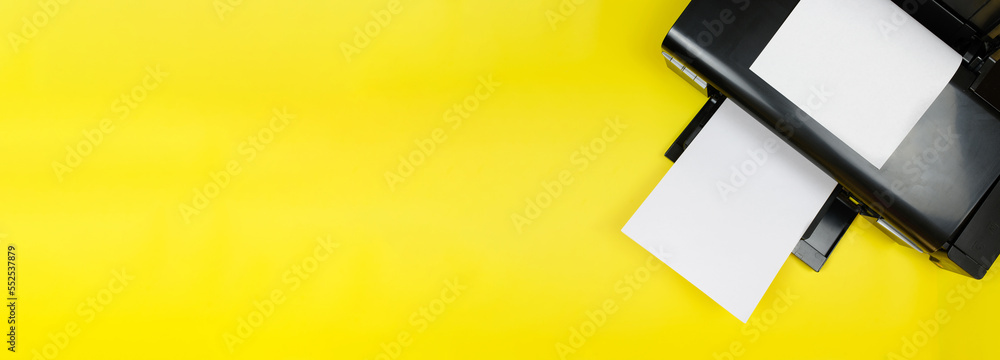 Top view of the printer and a blank sheet of a4 paper on a yellow ...
