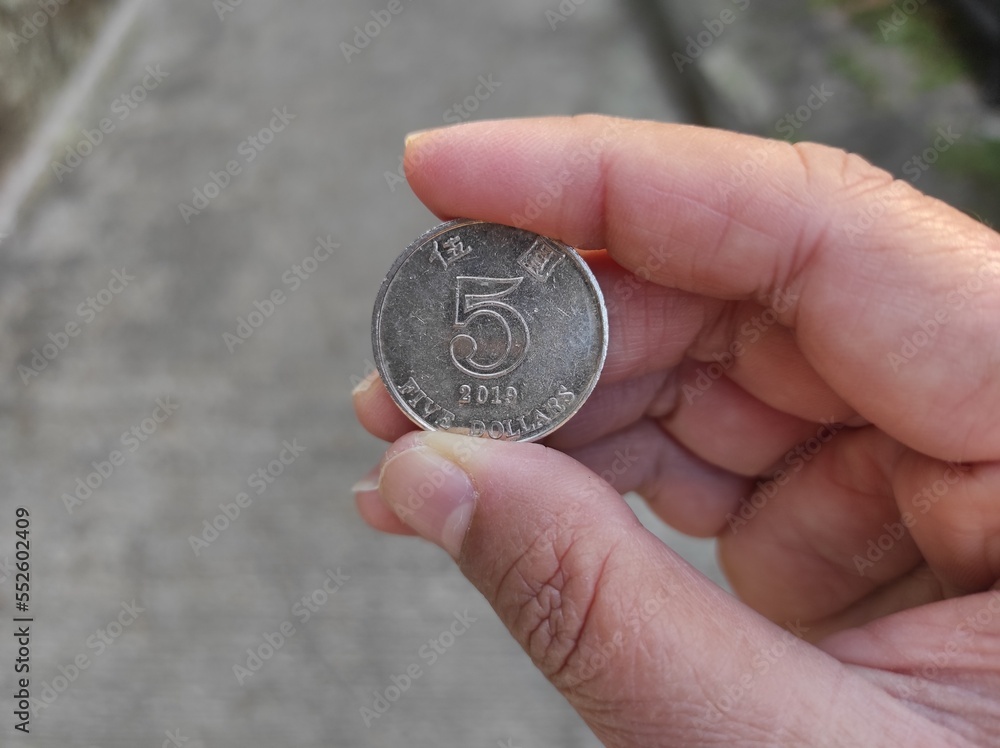 Hong Kong 5 dollar coins banknote in human hand on blurred background ...