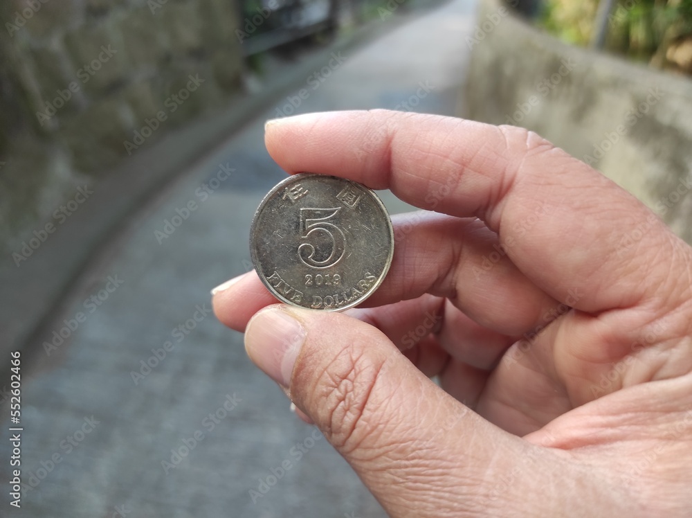 Hong Kong 5 dollar coins banknote in human hand on blurred background ...