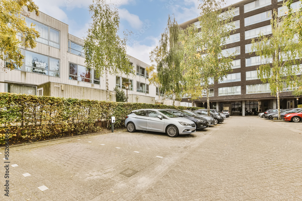 some cars parked in front of an office building with trees and bushes ...