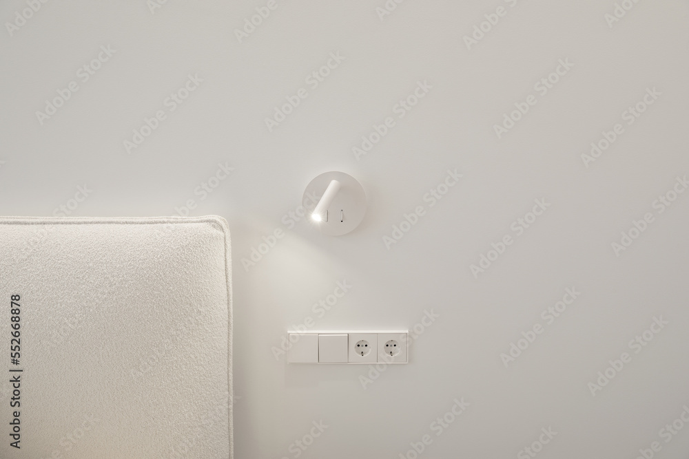 Bedside white LED wall lamp illuminating. Creative modern wall light source in bedroom. White ...
