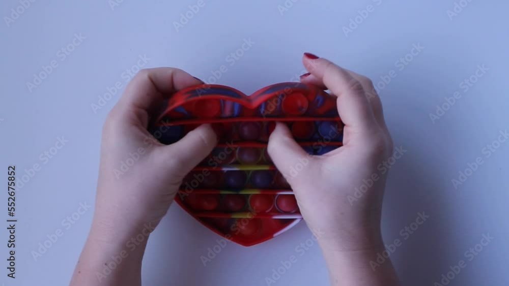 Women hands crumple and play with large heart Pop It close-up top view ...