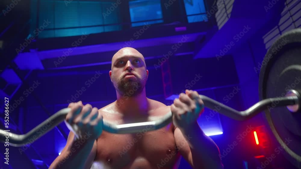 Muscular man with naked torso lifting heavy barbell with black round ...