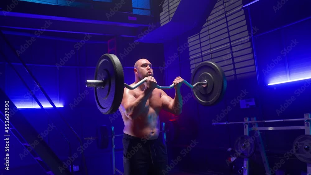 Muscular man with naked torso lifting heavy barbell with black round ...