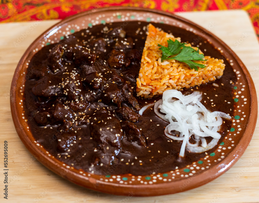 Mole poblano, cebolla y ajonjolí, en un plato de barro decorado ...