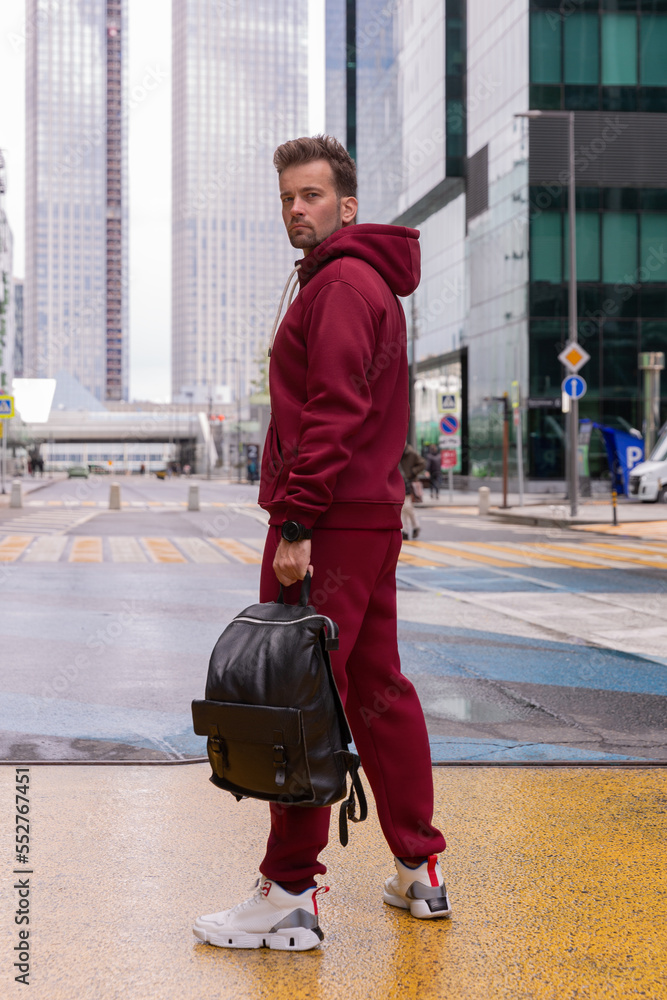 Full-length young man wears a vinous red sports suit and poses for the ...
