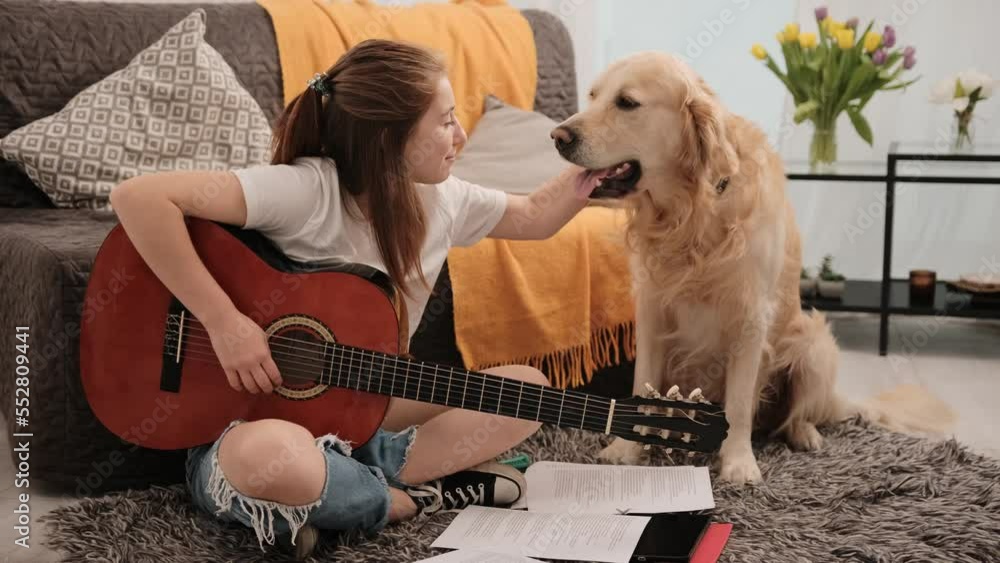 Young girl teenager holding guitar and petting golden retriever dog ...