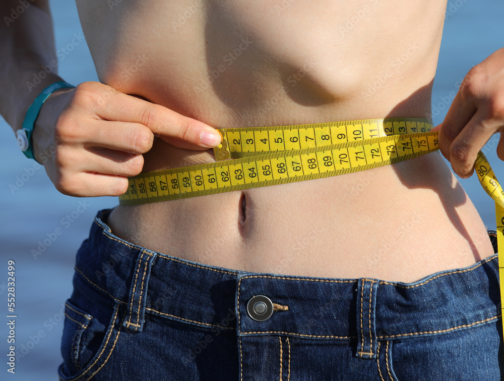 Fotka „thin anorexic girl measuring her very narrow waist with a yellow flexible meter“ ze ...