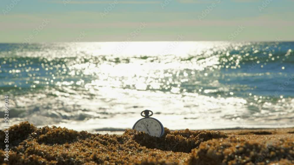 old vintage shiny stopwatch lies on sandy beach half buried in sand ...