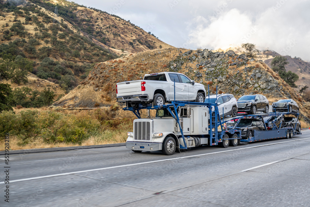 Classic powerful big rig car hauler semi truck transporting crossovers ...