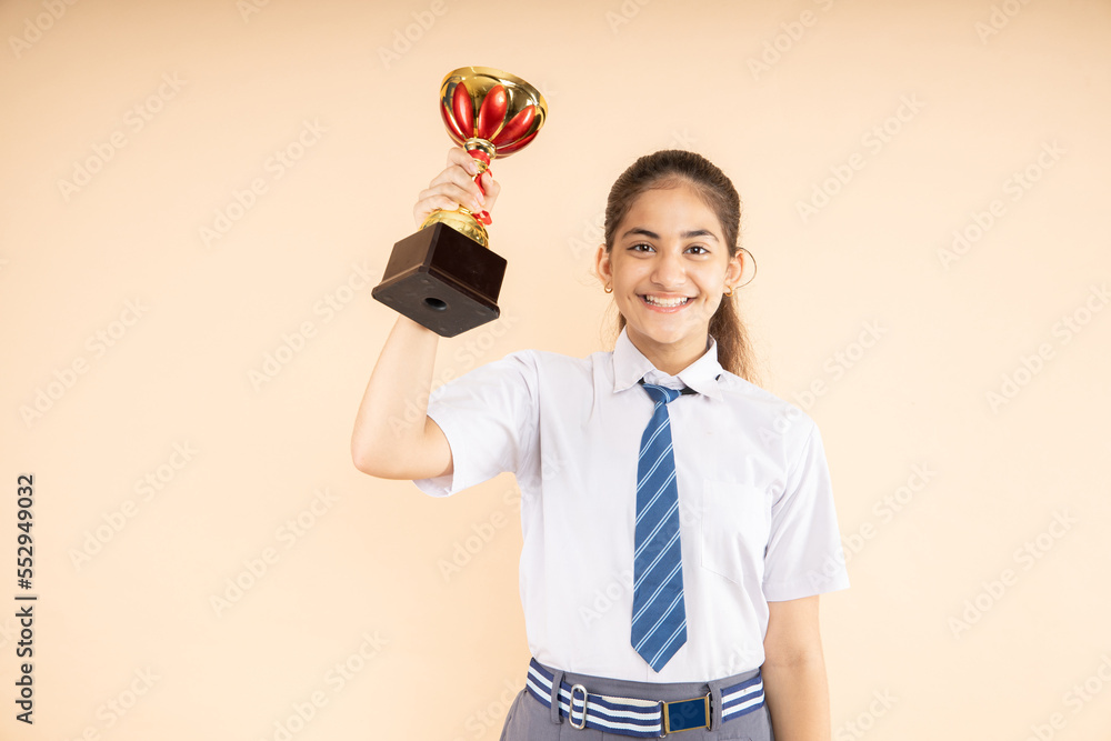 Happy Indian student schoolgirl wearing school uniform holding victory ...