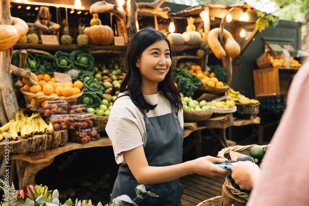 Outdoor market owner receiving payment from the buyer. Asian woman in ...