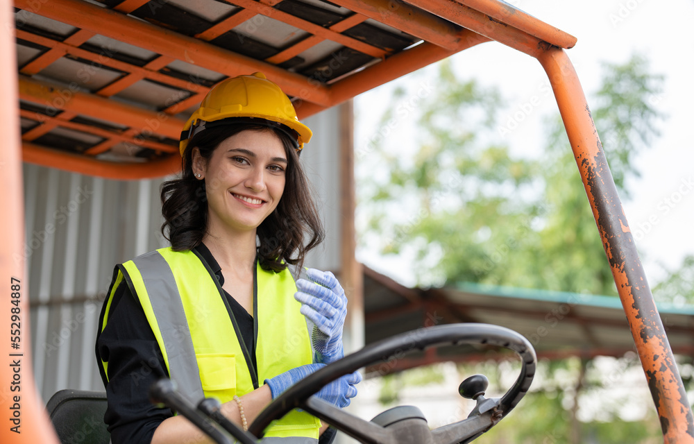 Beautiful female worker driving forklift truck in industrial factory ...
