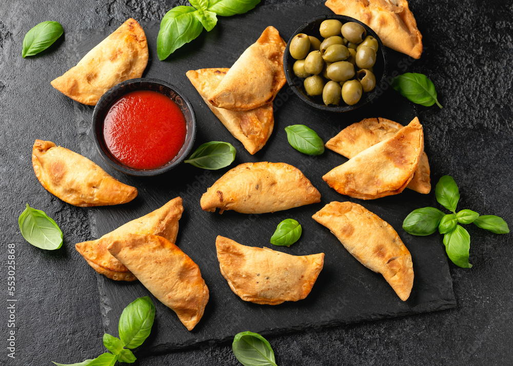 Freshly baked mini calzones with bolognese served on black slate board ...