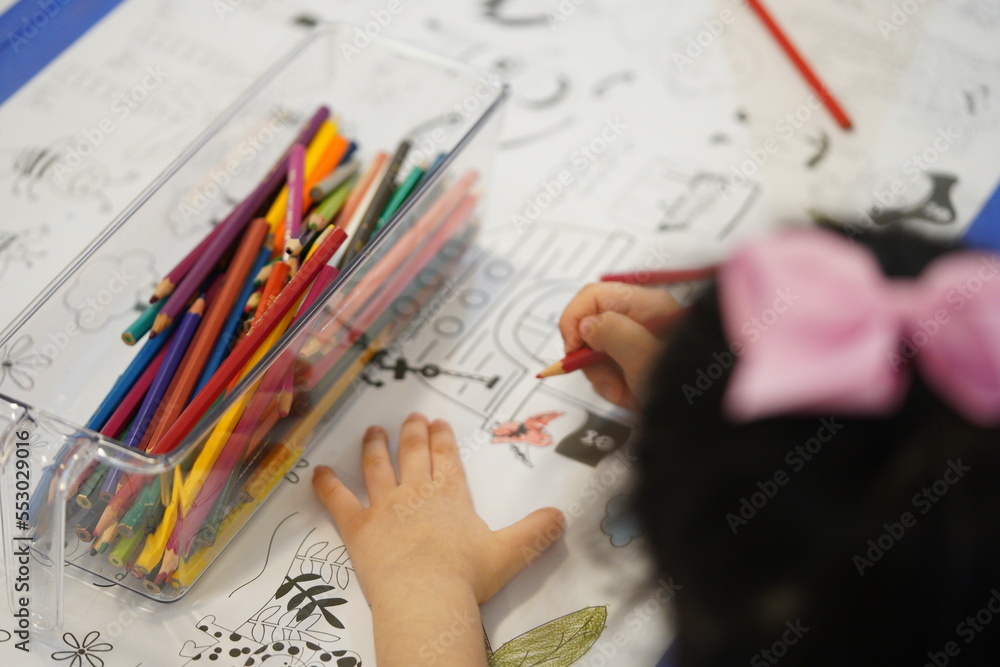 A child sits and colours a giant colouring paper pattern. Child holds a ...