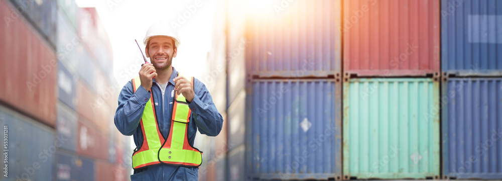 young harbor worker talking on the walkie-talkie at container warehouse ...