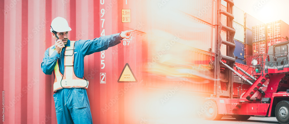 young harbor worker talking on the walkie-talkie at container warehouse ...