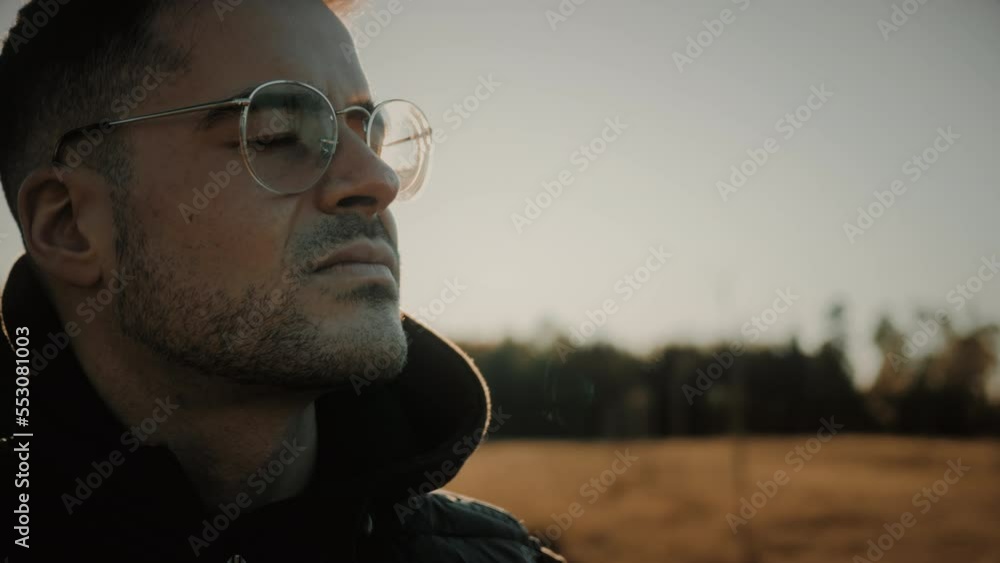 A young Caucasian man spends time alone outdoors reflecting on his life ...