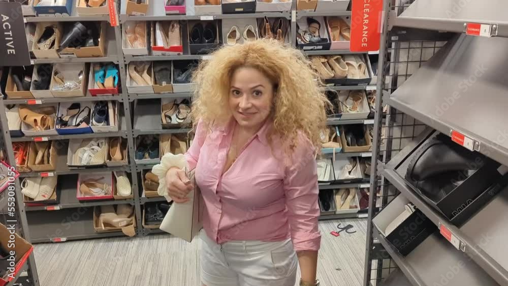 Latin woman shops for shoes and smiles at the camera as she takes her ...