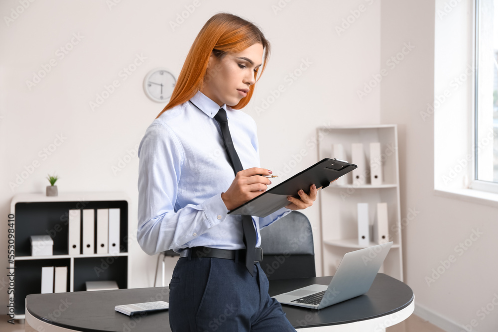 Foto de Beautiful transgender secretary with clipboard in office do ...