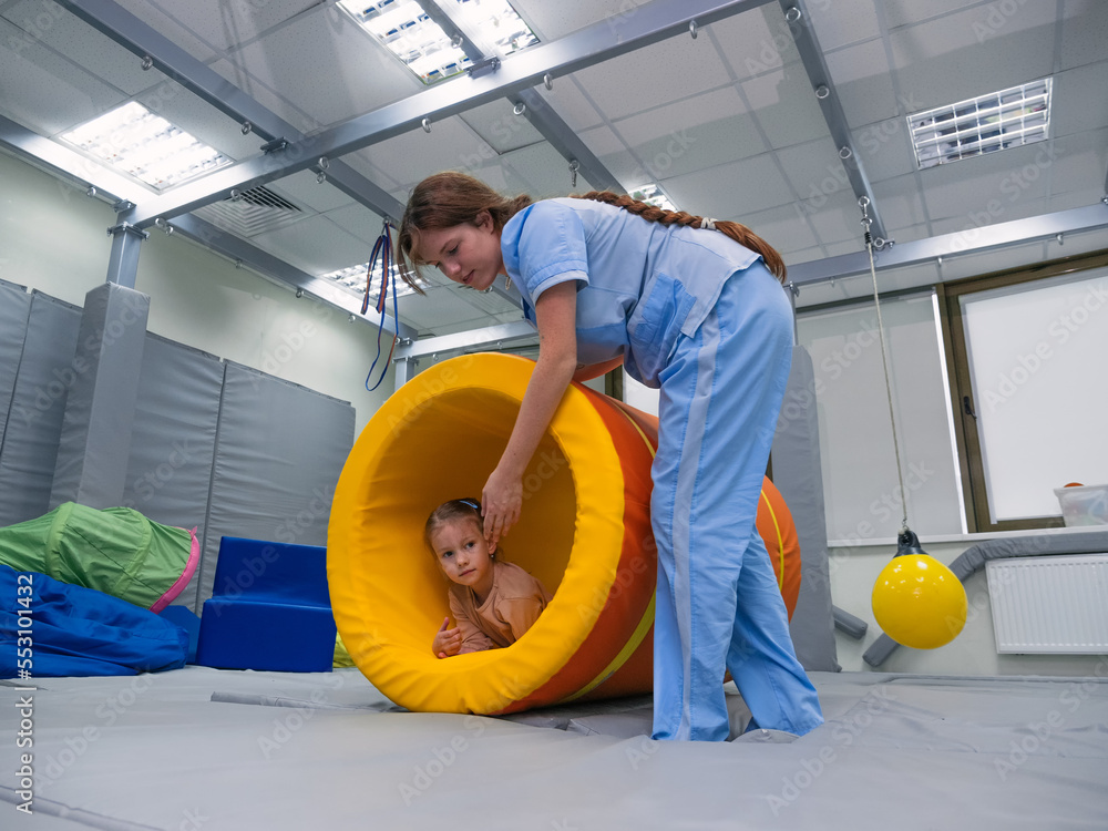 Foto de Kid girl rotation in roller tonnel during sensory integration ...