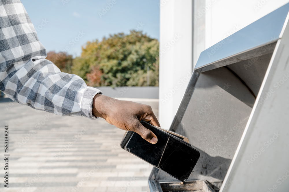 Hand of man throwing mobile phones in garbage bin Stock Photo | Adobe Stock