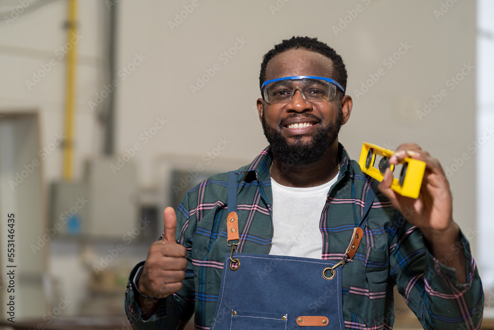 Portrait of African American carpenter holding precision level making ...