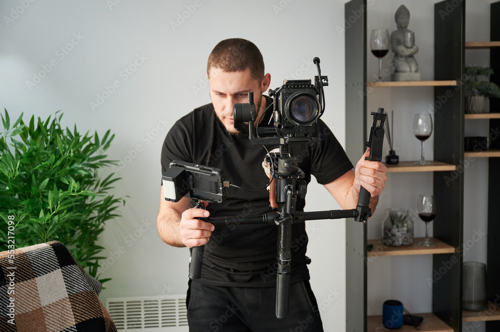 Videographer man shooting footage indoors, using camera mounted on ...
