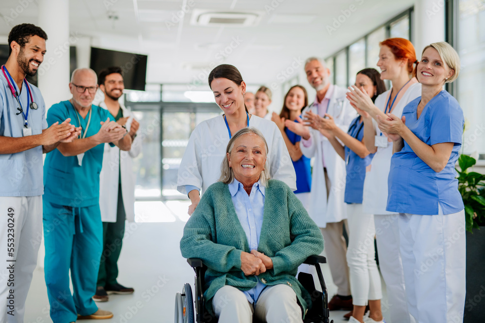 Medical staff clapping to senior patient who recovered from serious ...