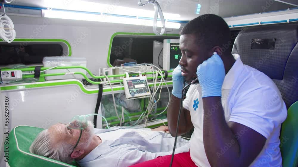 Professional African-American paramedic providing first aid mature ...