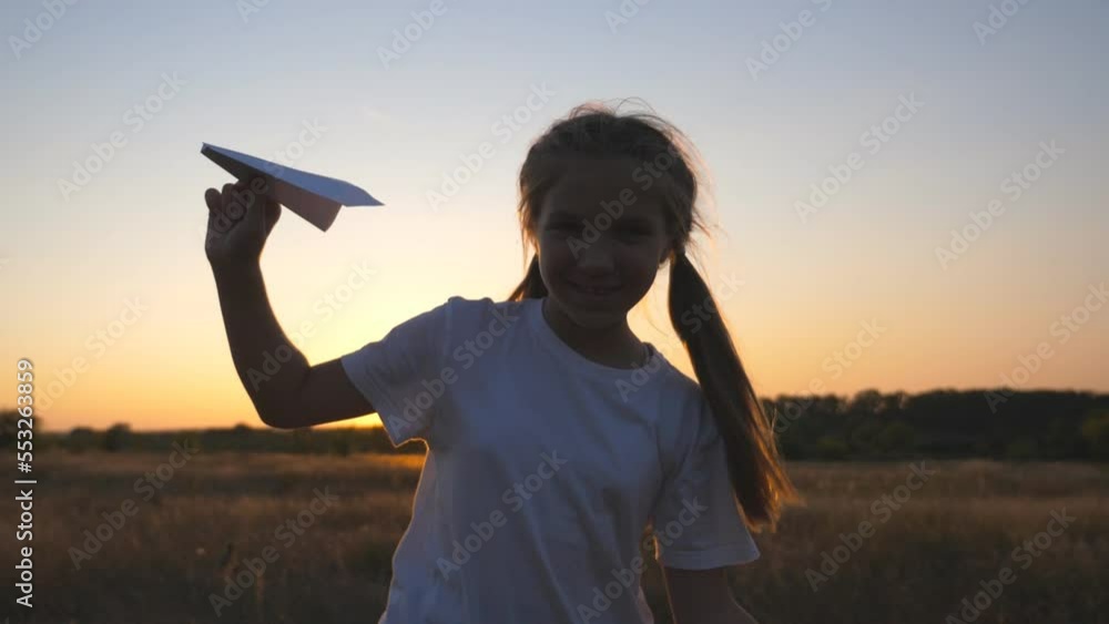 Happy small girl running with paper airplane through grass field ...