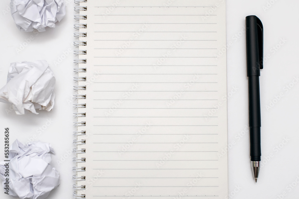 Blank open notepad, pen and crumpled paper wads on white background ...