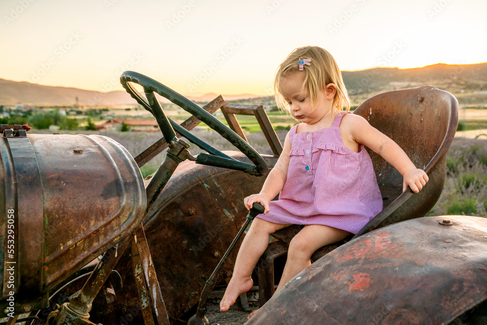 A small child farmer operates agricultural machinery. Cute girl on an ...