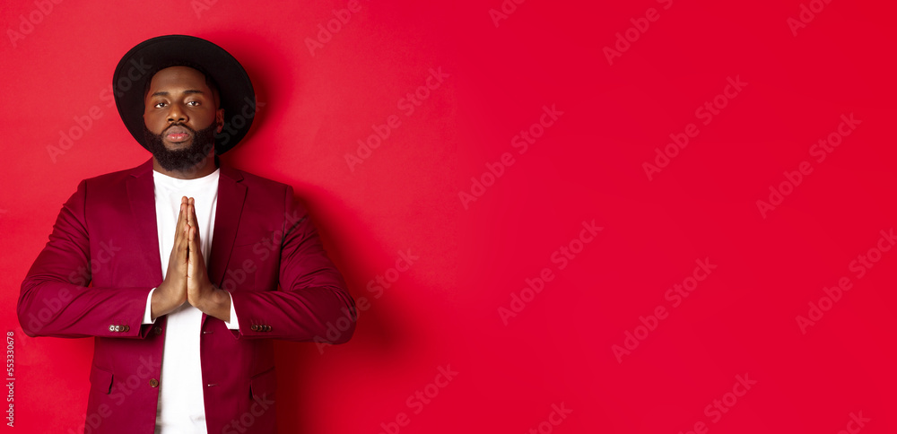 Serious african american man showing respect, holding hands together in ...